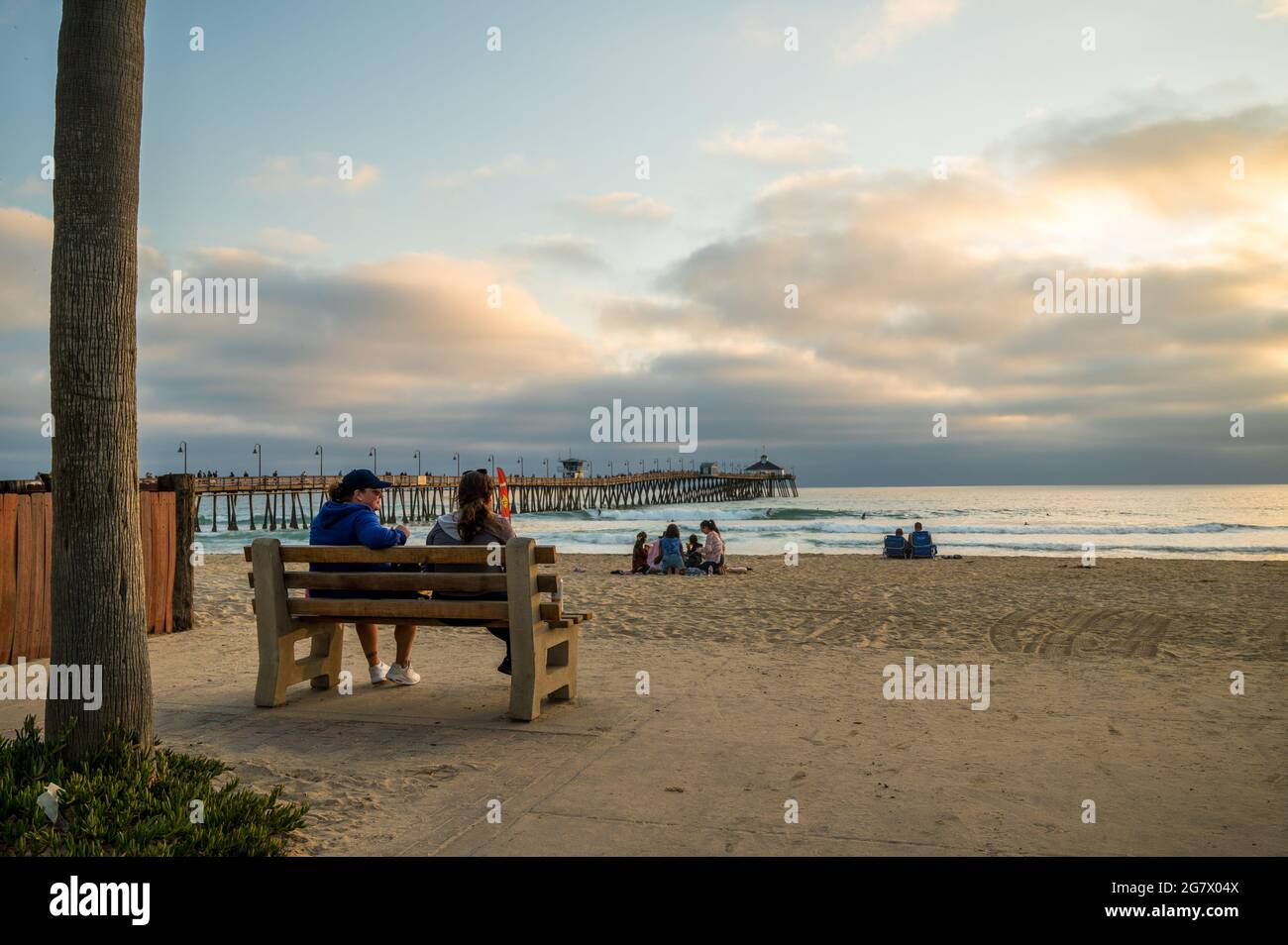 People sit on a bench at beach enjoying scenery and sunset Stock Photo ...