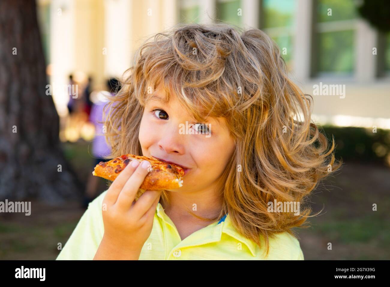 Child boy eating a piece of pizza. Kid eats a slice of pepperoni pizza ...