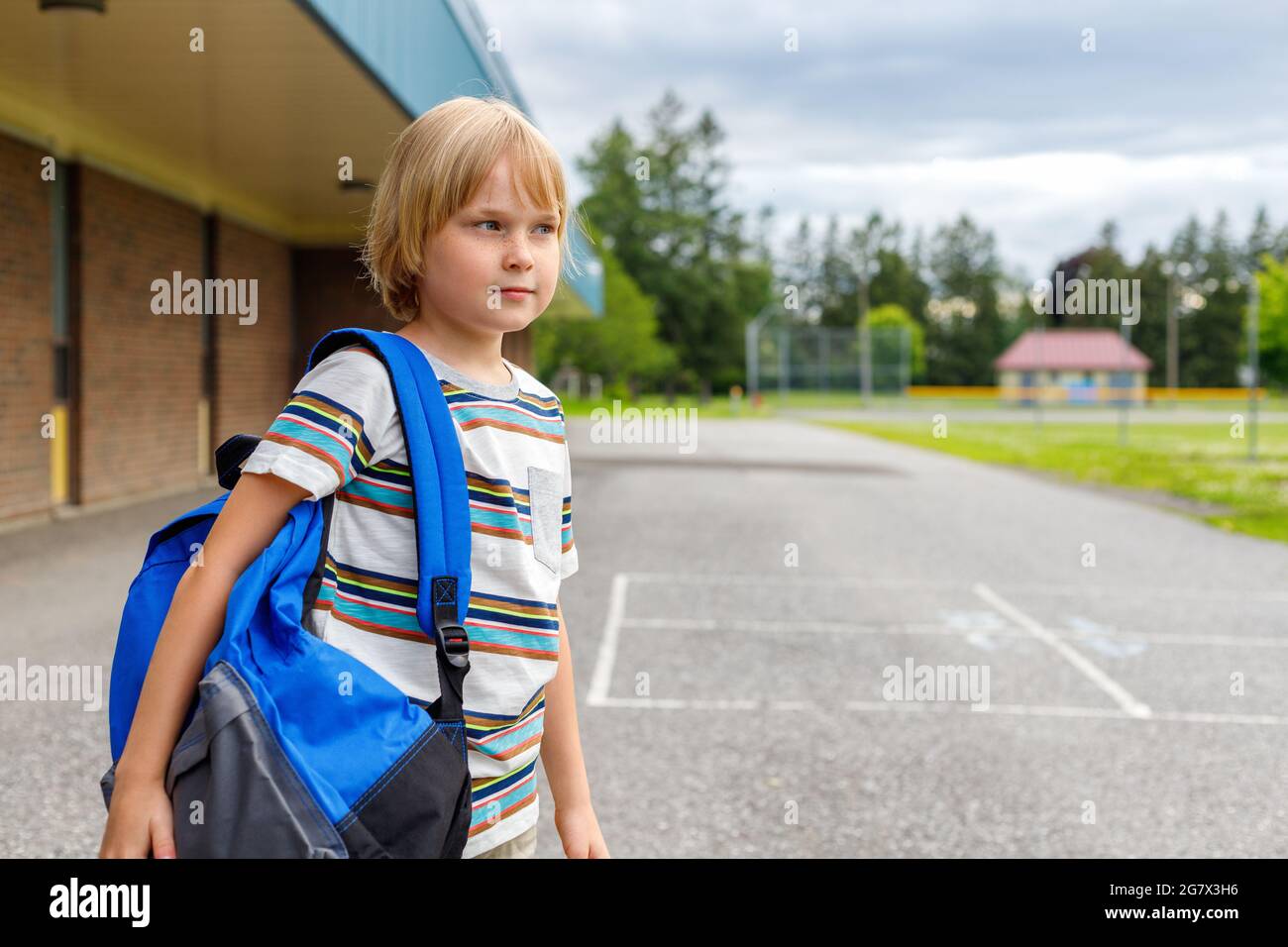 Beautiful child near school building at schoolyard. Little student ...