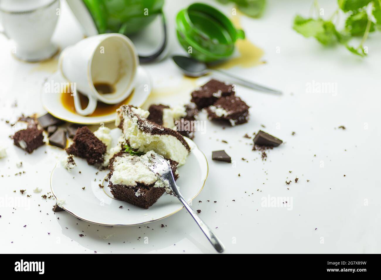 Messy table with cake pieces, a turned cup of tea, and a teapot Stock ...