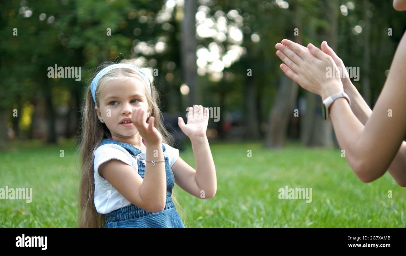Pretty little child girl playing game with her mom with their hands ...