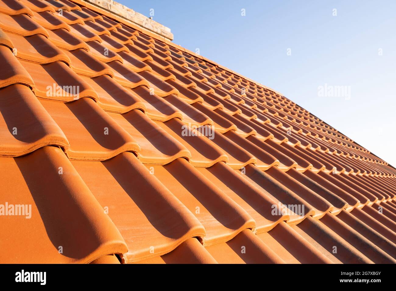 Overlapping rows of yellow ceramic roofing tiles covering residential ...