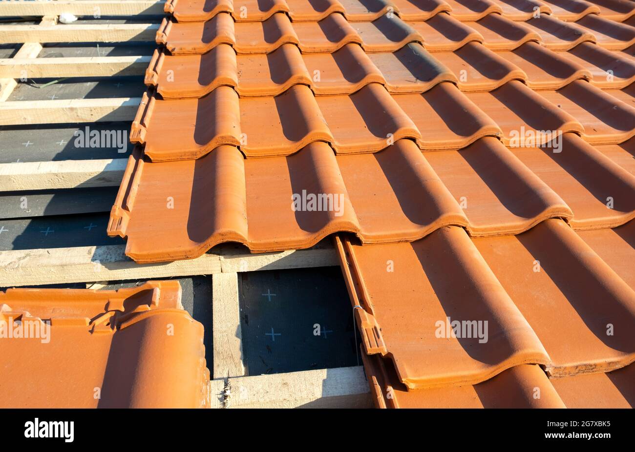 Overlapping rows of yellow ceramic roofing tiles mounted on wooden ...