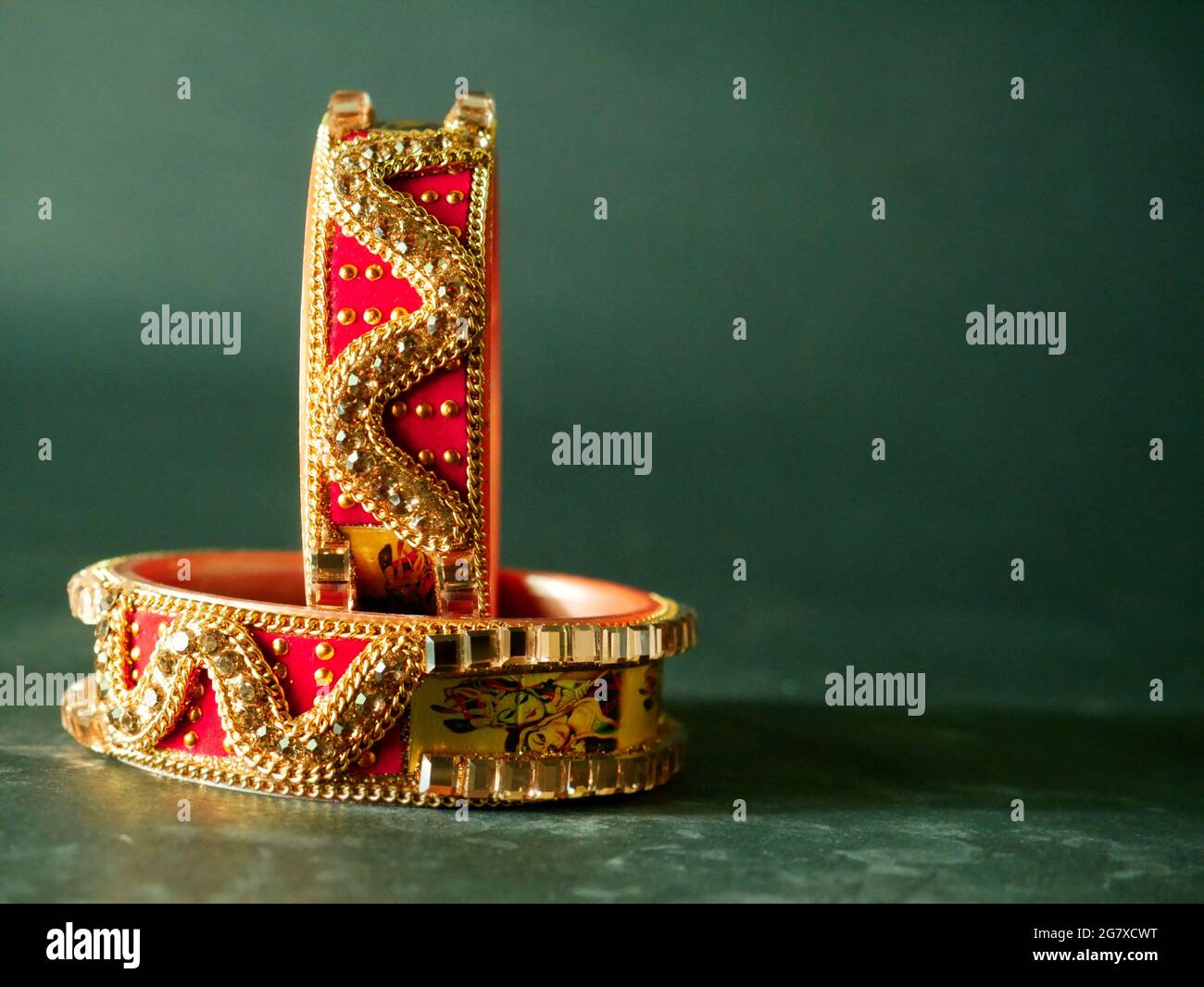 Red color fancy pattern female hand wearing sets at dark backdrop ...