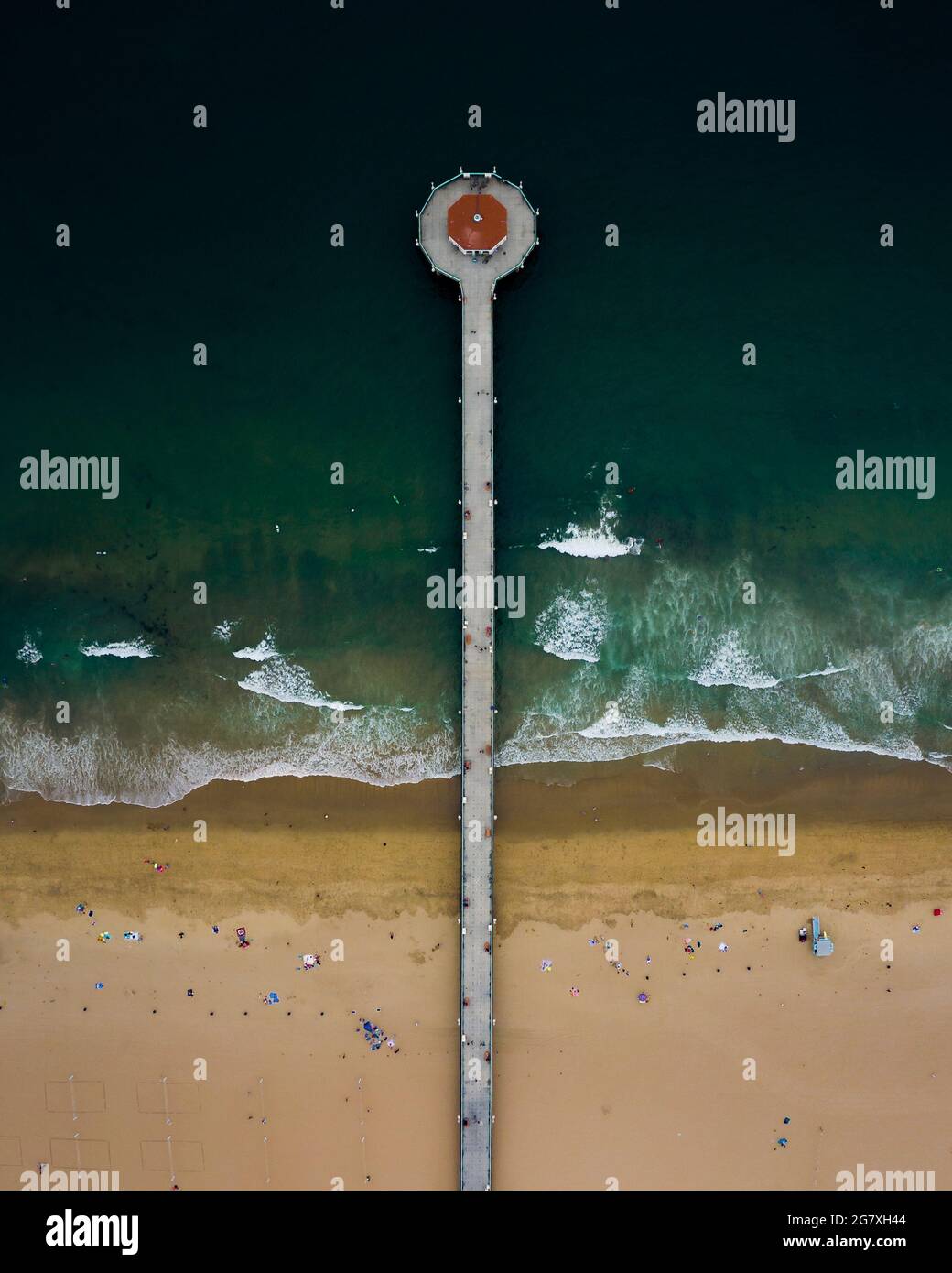 Aerial shot of a long wooden pier with an alcove over a gloomy green ...