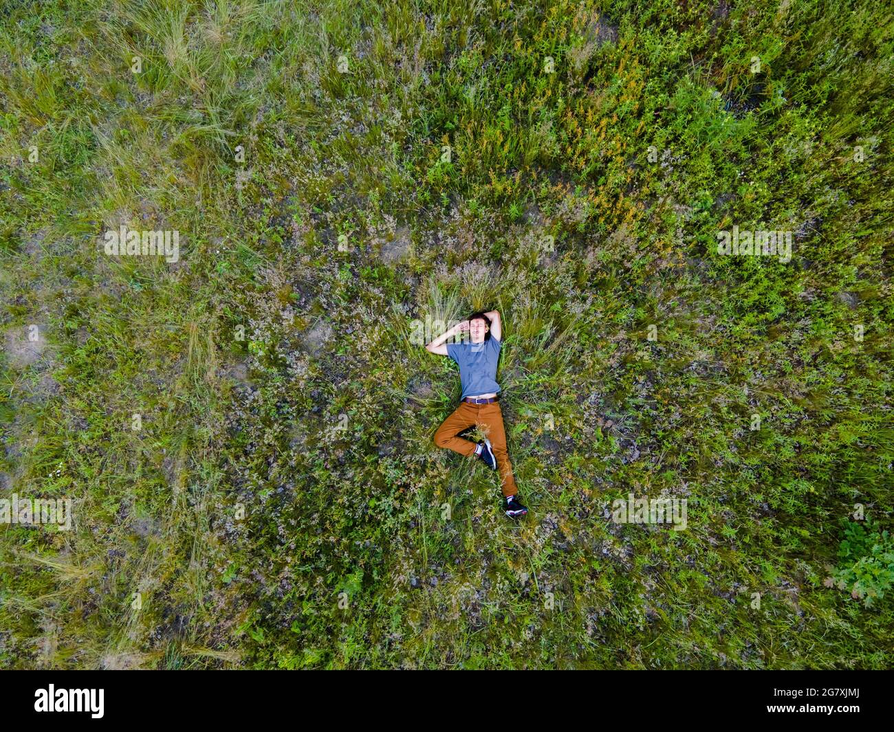 Aerial view from a drone of a man lying on his back in tall grass Stock ...