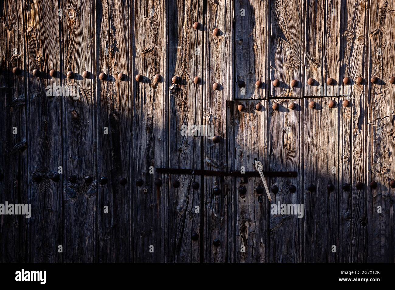 Old and decrepit wooden gate, half lit by the sun, in an unpopulated ...
