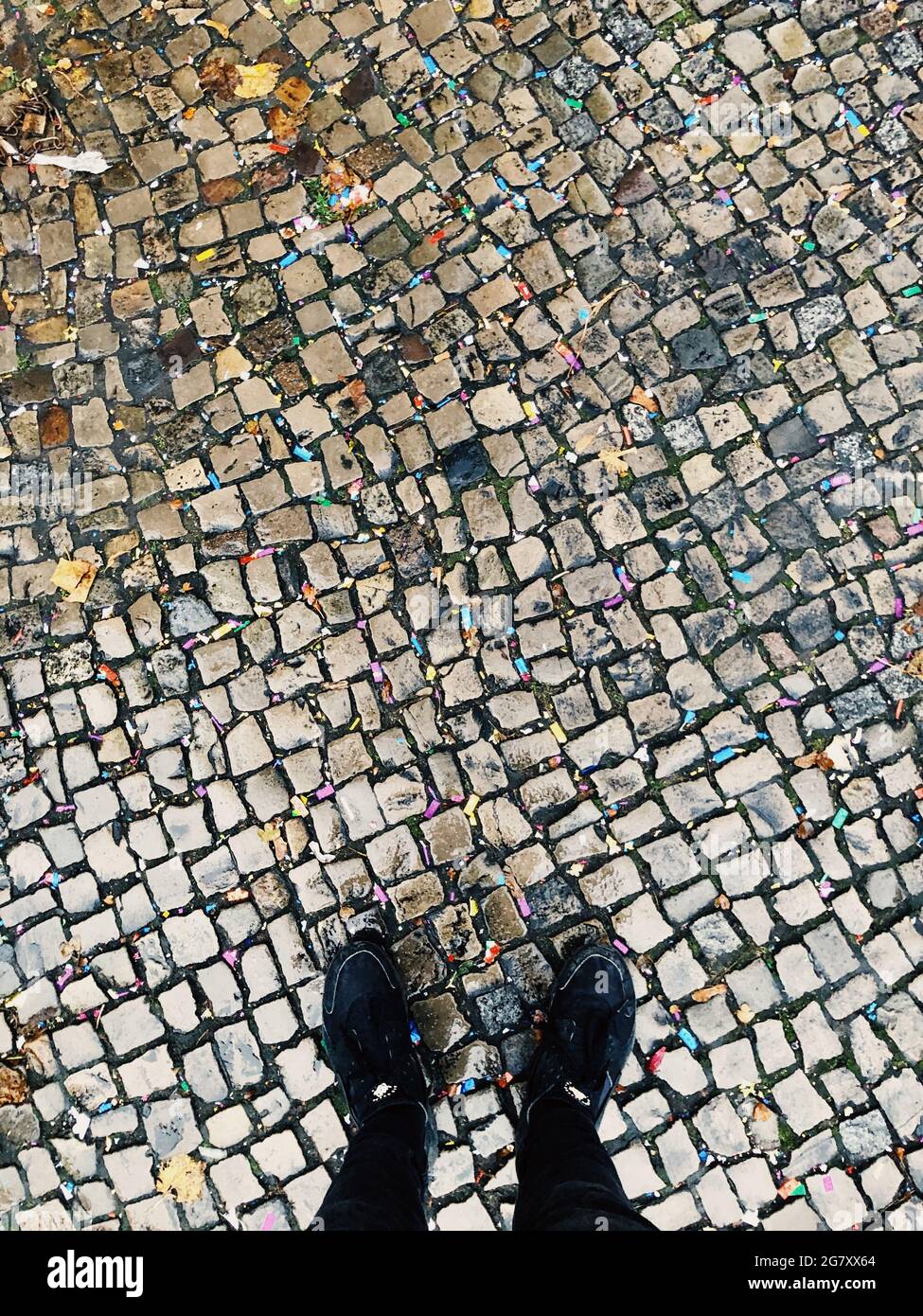 High angle shot of pair of human feet in black shoes on a pavement ...