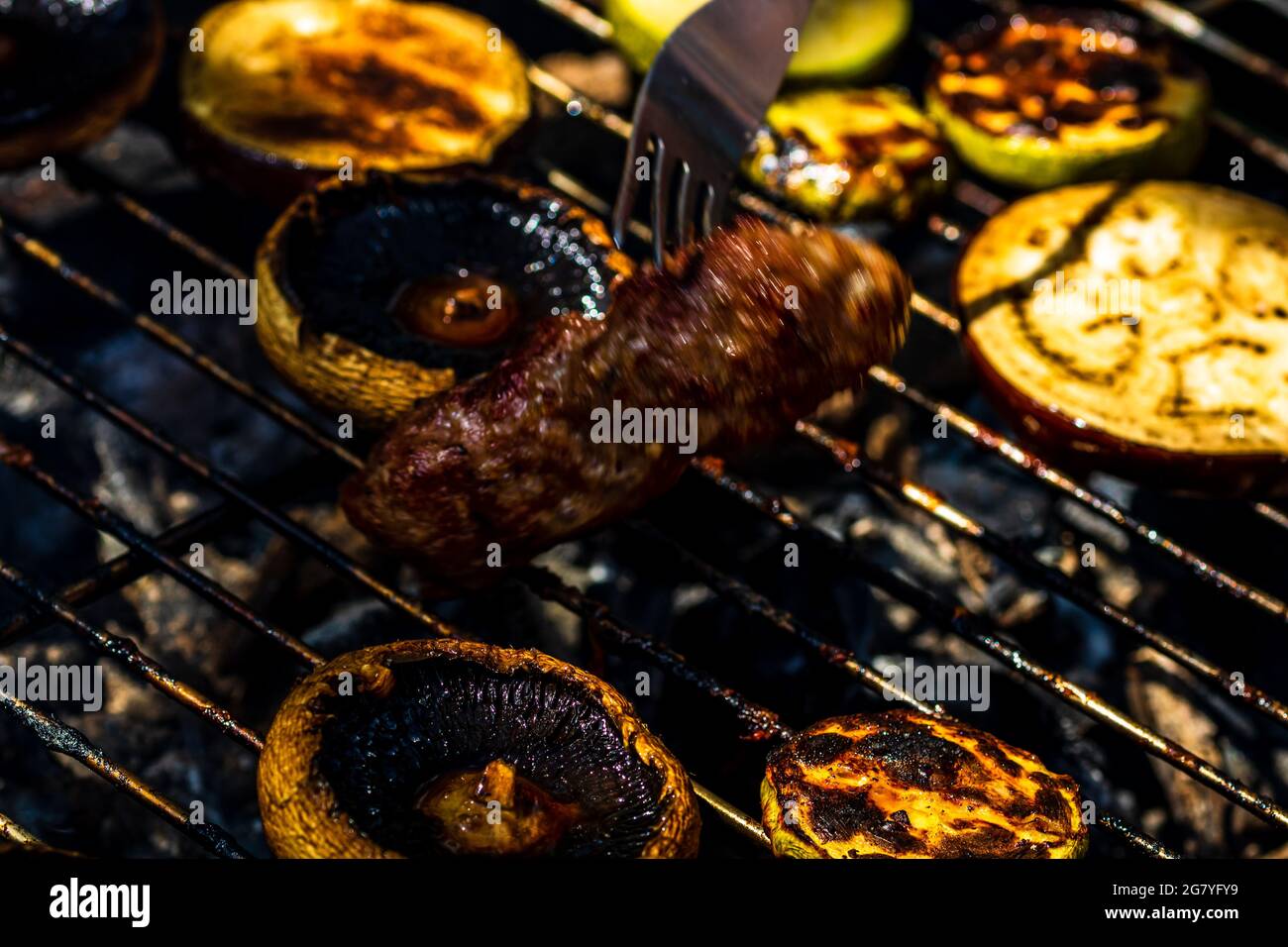 Grilling meat rolls called mici or mititei with vegetables on char ...