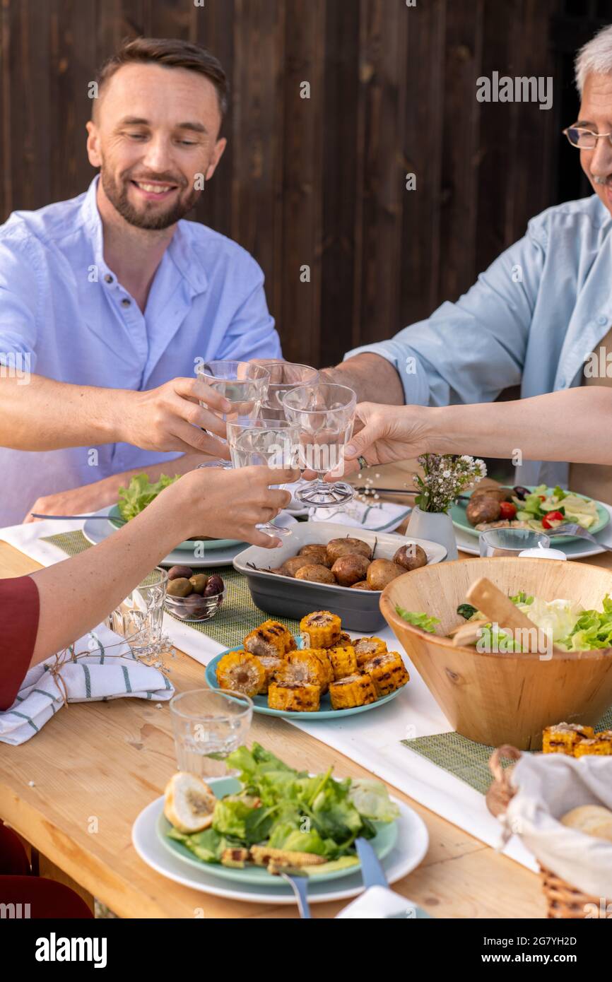 Group of people toasting with glasses of alcohol over dinner table when ...