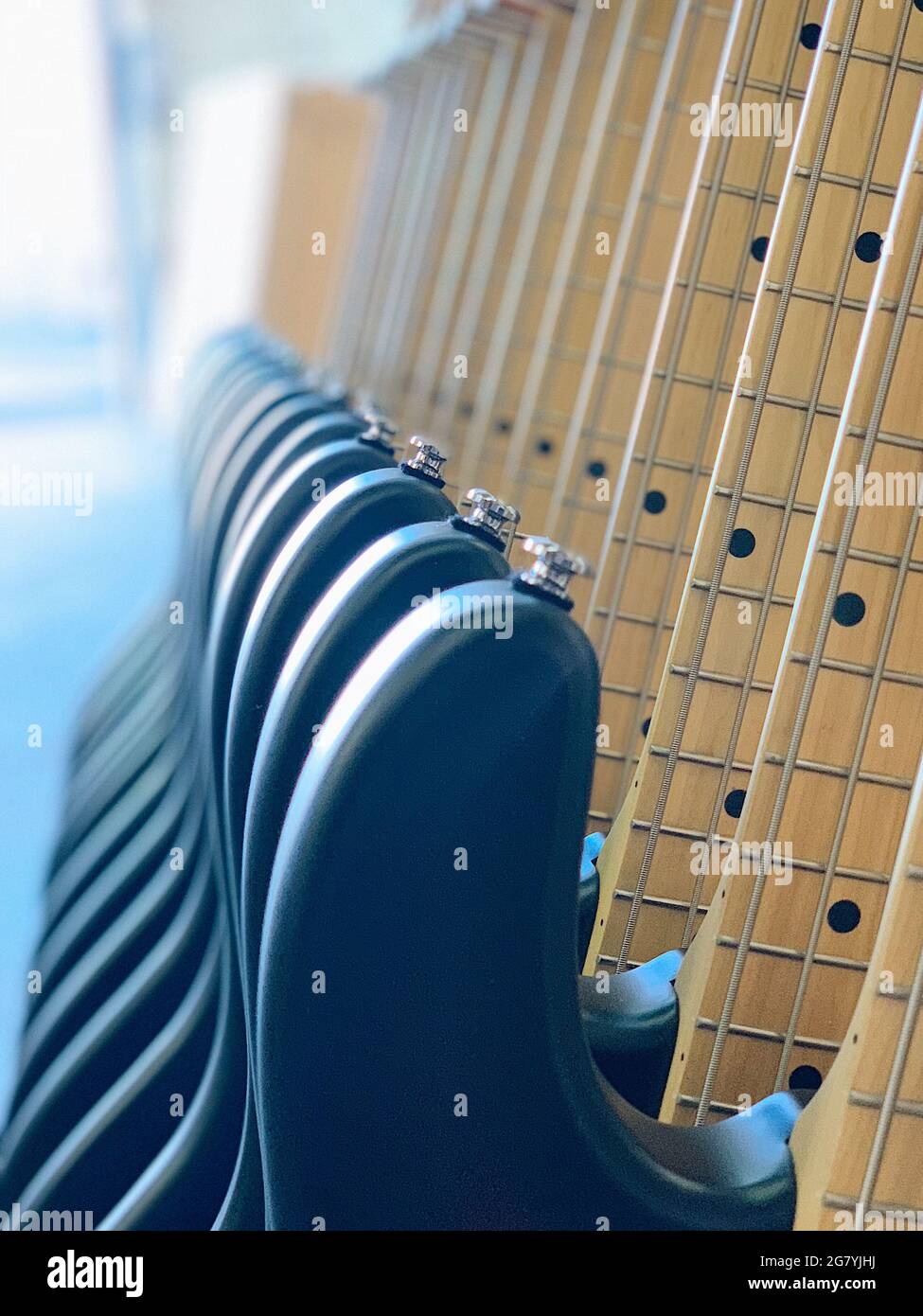 a closeup of a lineup of bass guitars on a rack Stock Photo - Alamy