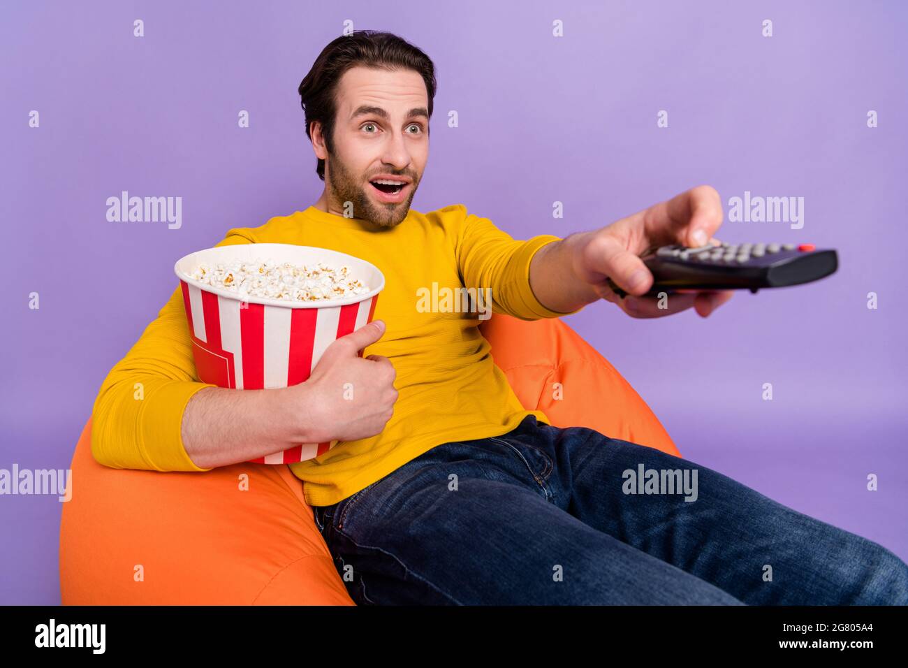 Portrait of attractive amazed cheerful man having fun eating corn ...