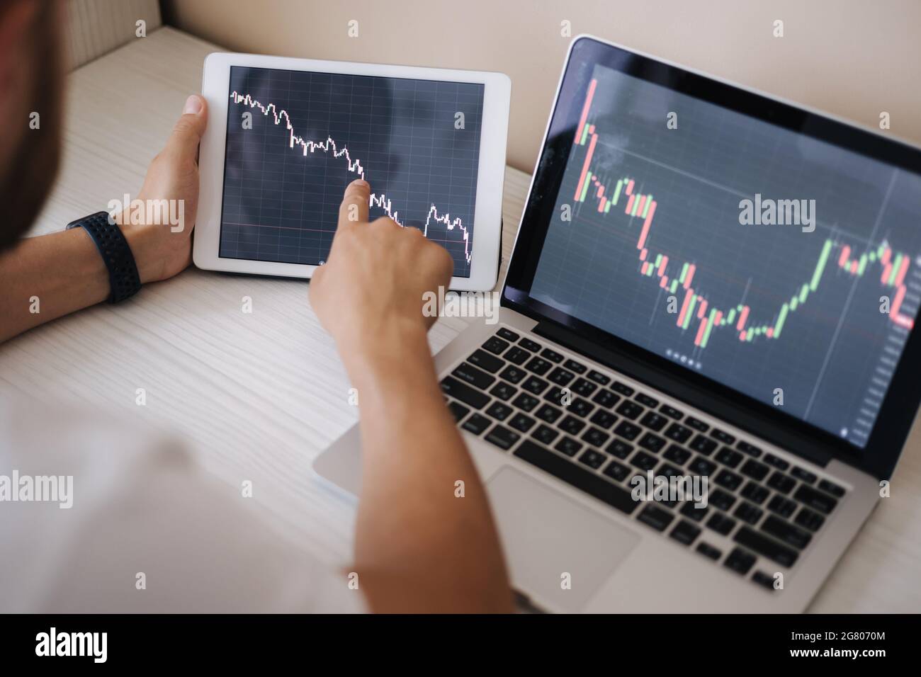 Young adult man trading on line with tablet pc connected to stock ...