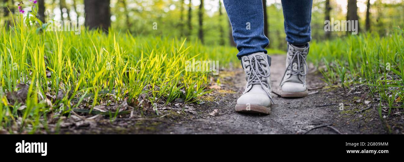 Hiking boot on footpath. Panoramic view of hiker legs walking at ...