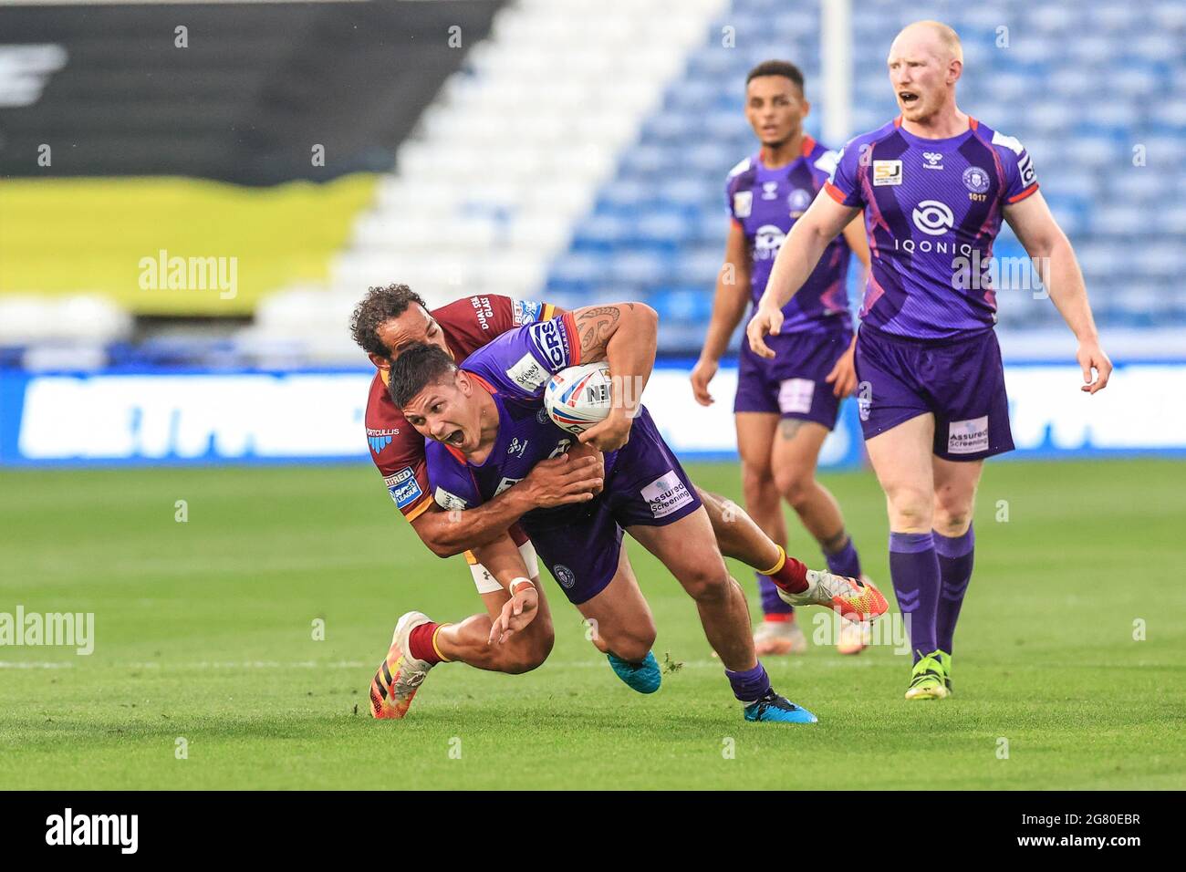 Mitch Clark (23) of Wigan Warriors is tackled by Leroy Cudjoe (21) of ...