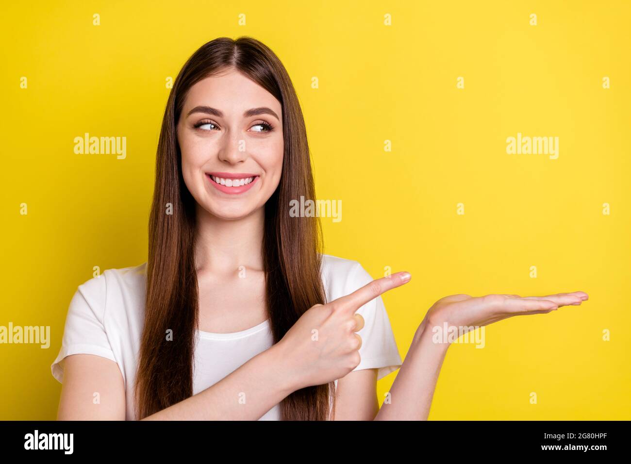 Portrait of attractive cheerful girl holding on palm demonstrating copy ...
