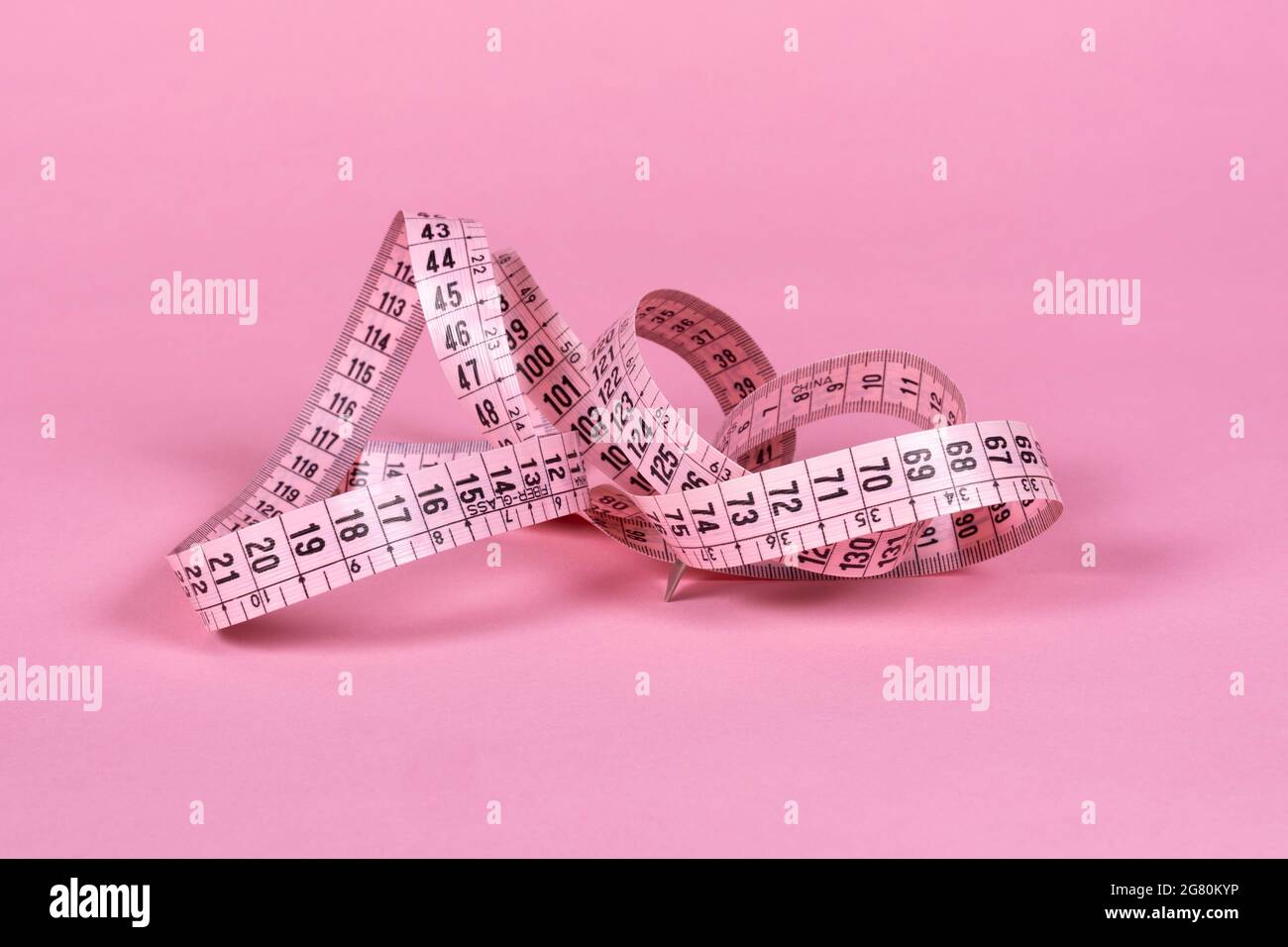 Rolled measuring lint isolated in a pink background with shadow Stock ...
