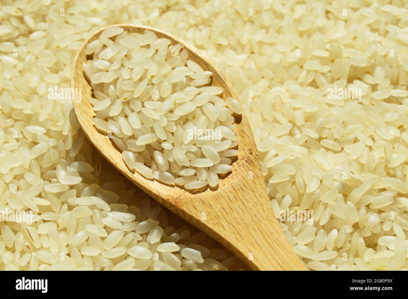 Fresh organic white raw dried rice grains texture and wooden spoon ...