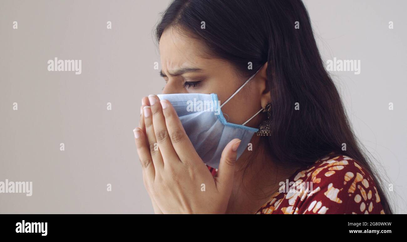 Young Indian with a mask coughing on a white wall background Stock ...
