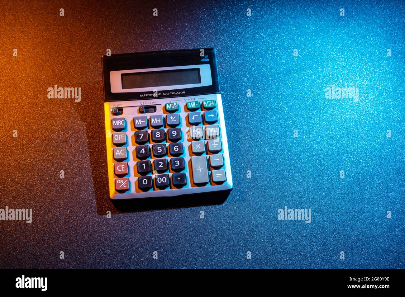 Calculator on a black background. Blue and yellow lights in the ...