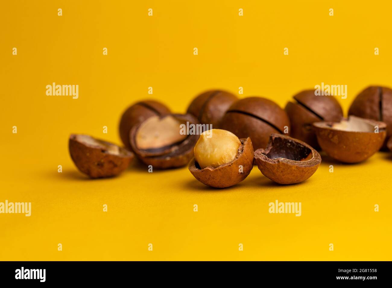 delicious macadamia nuts on a yellow background Stock Photo - Alamy