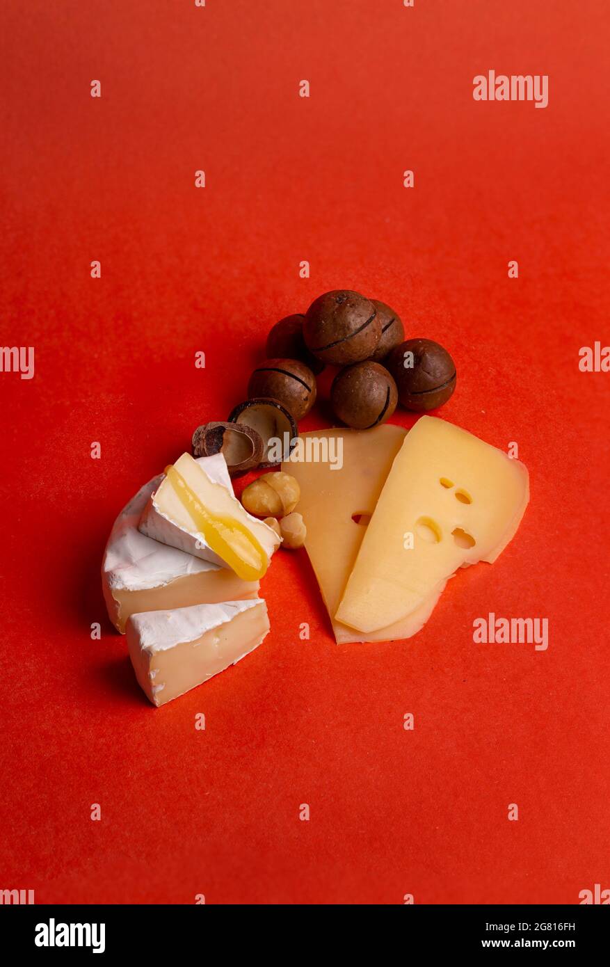 cheese with nuts and honey on a red background Stock Photo - Alamy