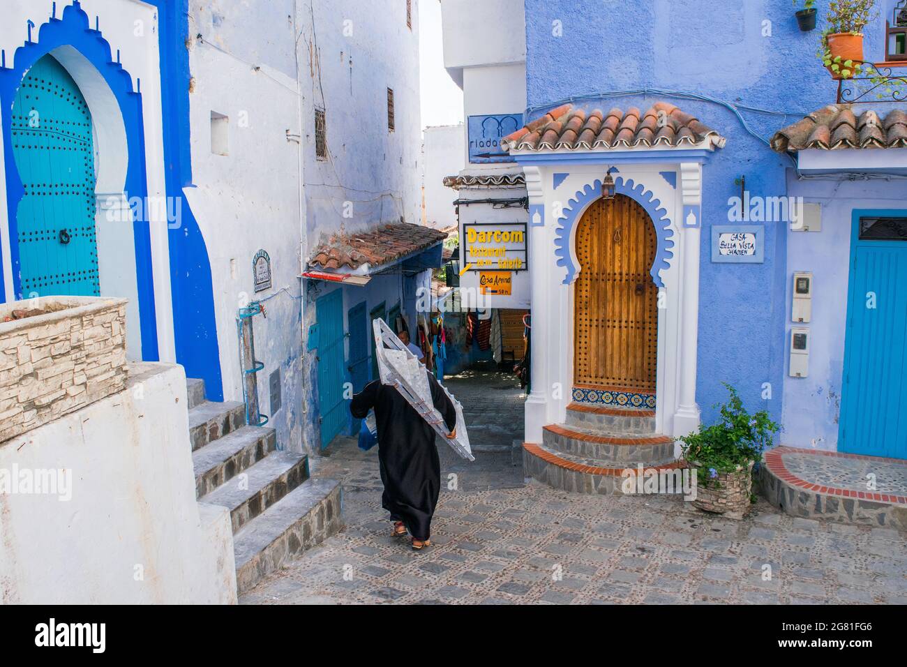 CHEFCHAOUEN, MOROCCO - Aug 31, 2018: A man carrying a ladder along a ...