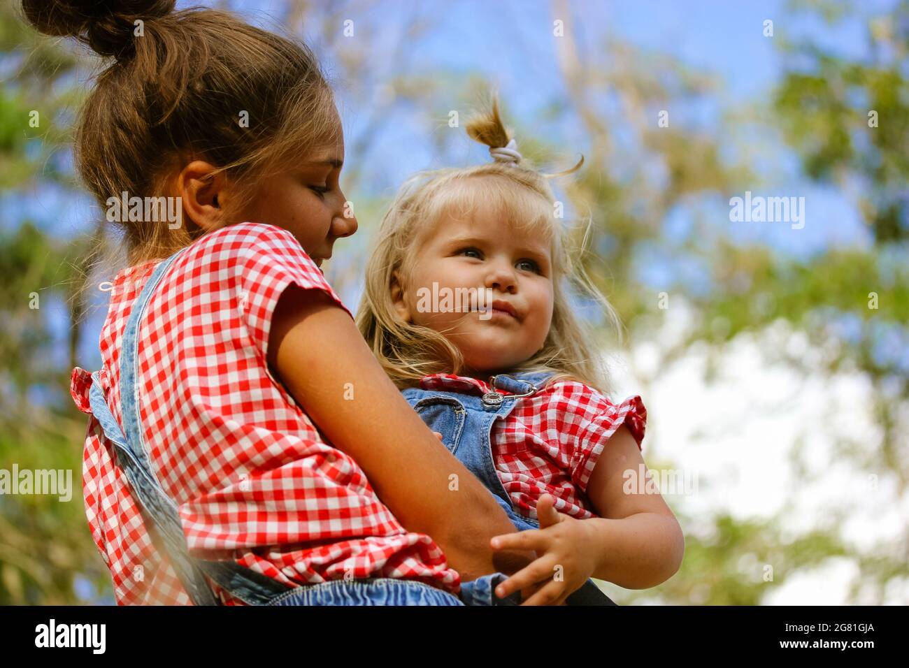 Two happy sisters in summer forest. Older teenage mestizo girl holding ...