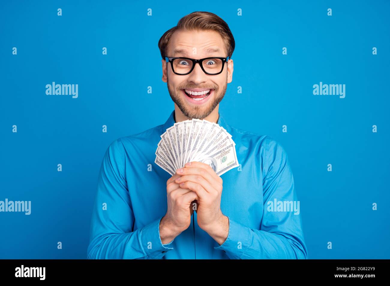 Photo of young excited man happy positive smile hold dollars banknotes ...