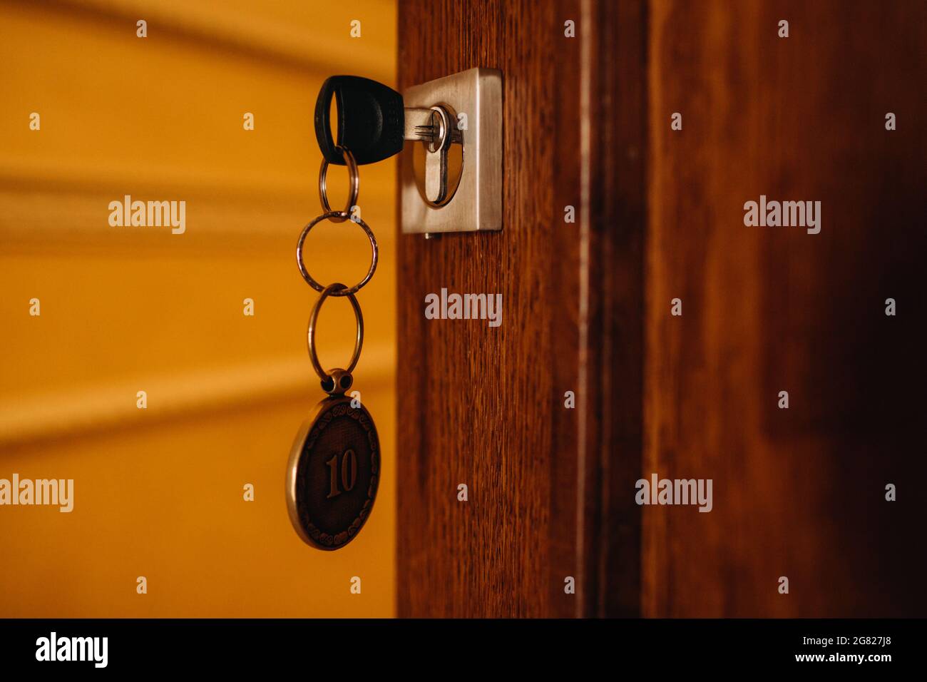 House key in the door. Key with key chain opens or closes the wooden ...