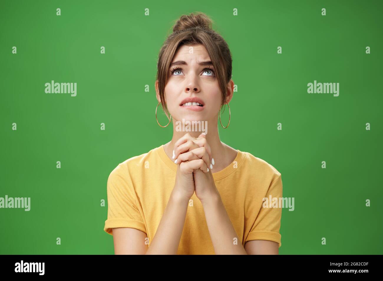 Intense nervous and faithful good-looking young woman clenching hands ...