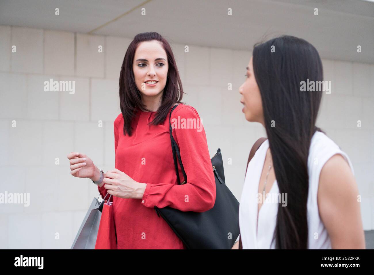 Two girls shopping outside a shopping area while having a conversation ...