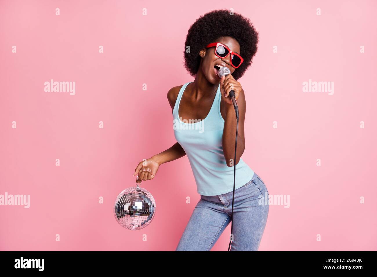 Photo of funky young dark skin woman wear jeans hold disco ball mic ...
