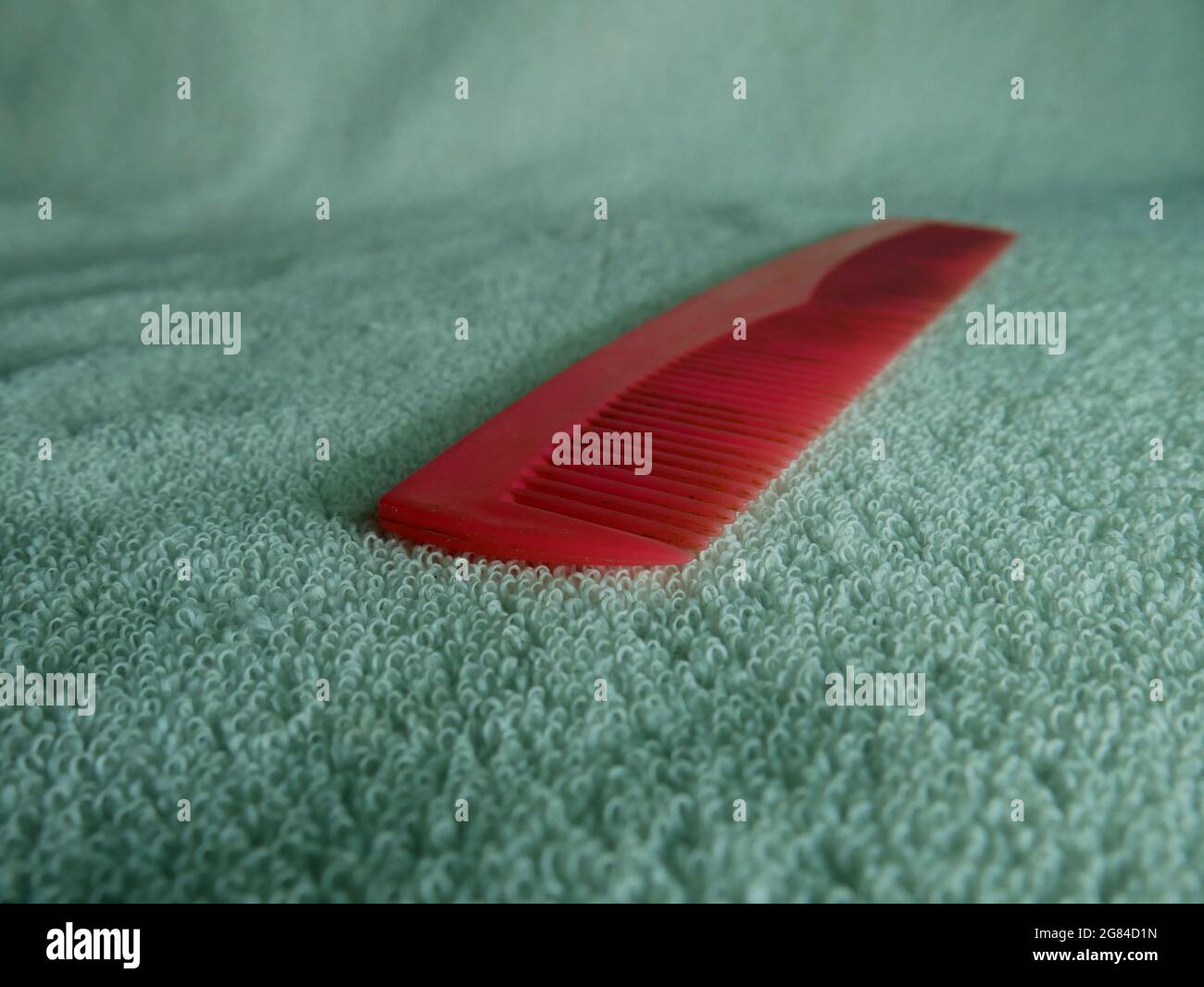 Red color comb kept at white fabric surface, Human lifestyle product ...