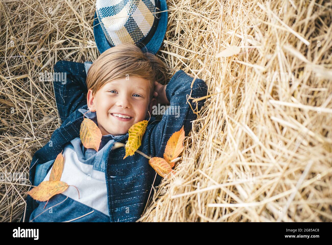 Kid boy lies on the hay. Cute little child boy on farm village ...