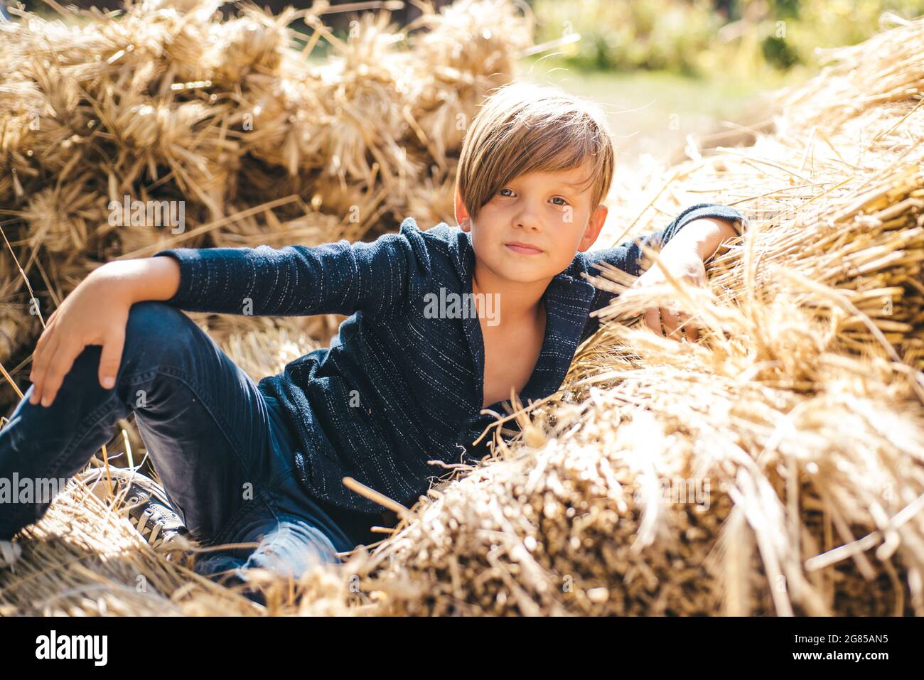 Kid boy lies on the hay. Boy in the hat are preparing for autumn sunny ...