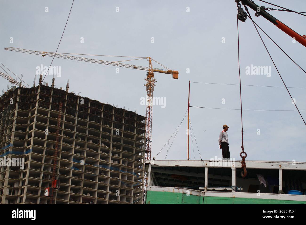 A man stand on top of fishing ships with construction site in the ...