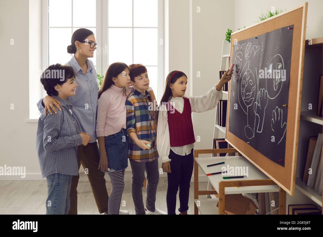 Elementary school girl student answering at board on lesson front of ...