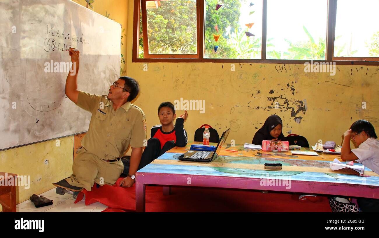 teacher with disabilities (without legs), eagerly teaches his students ...