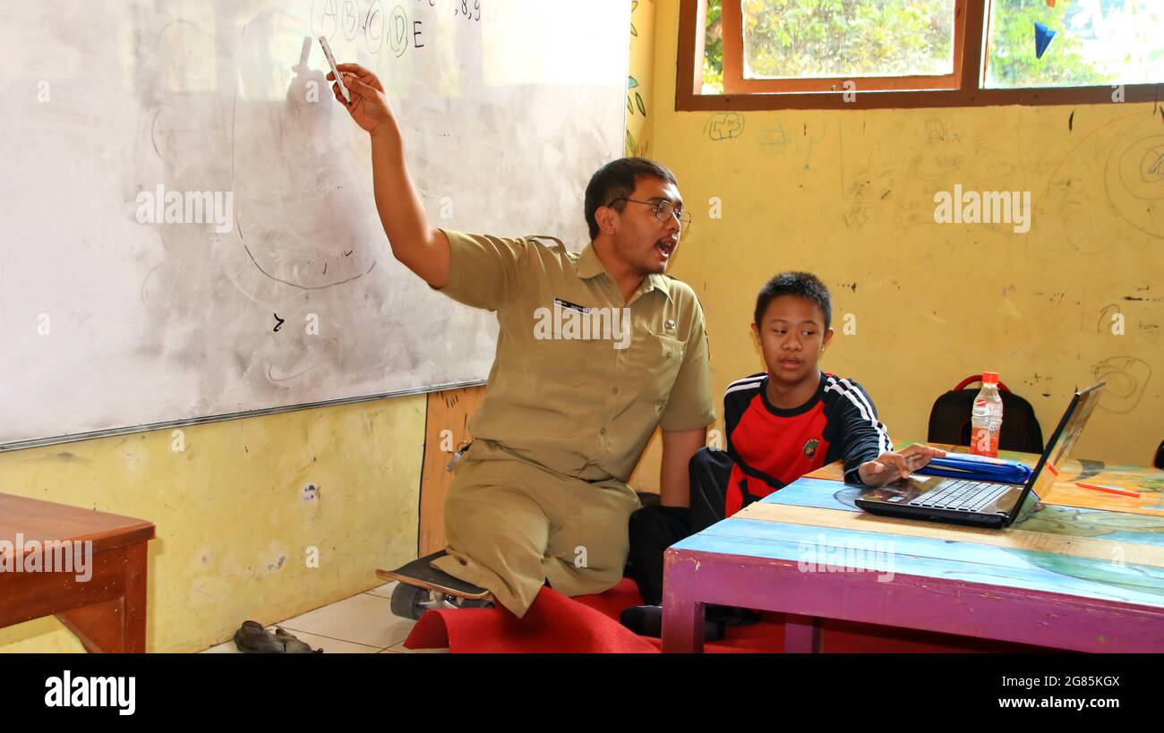 teacher with disabilities (without legs), eagerly teaches his students ...