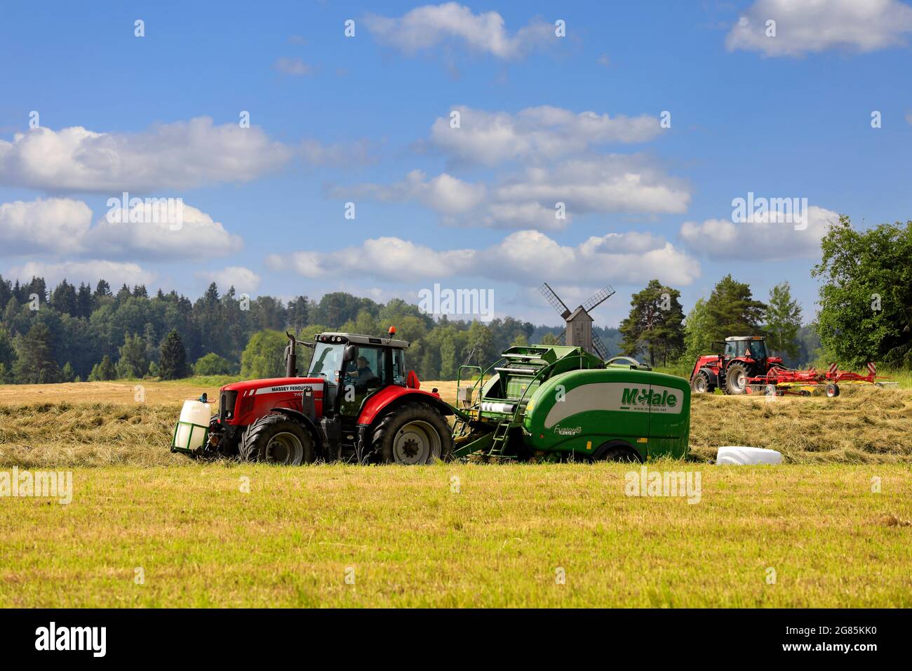 Massey-Ferguson tractors in hay field with McHale baler wrapper and a rotary rake harvesting dry ...