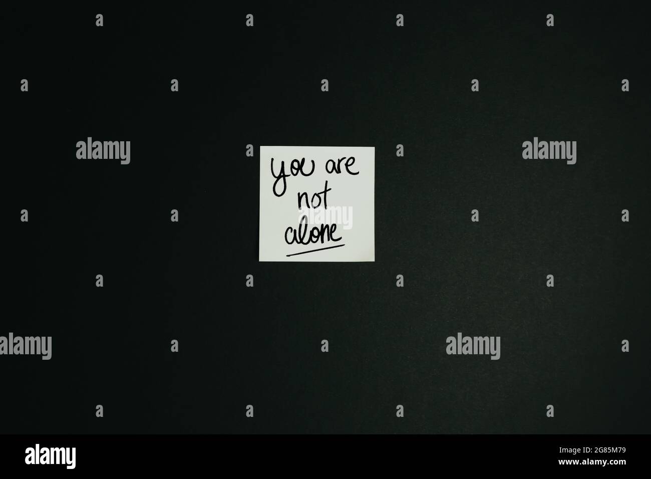 Encouraging YOU ARE NOT ALONE note written on white paper against a ...