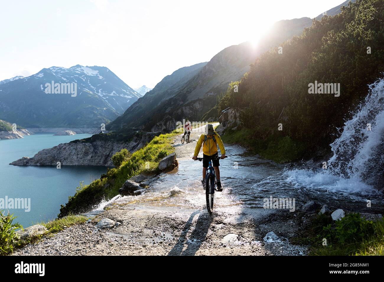 Boy on a mountain bike cycling on a gravel road over glacier creek ...