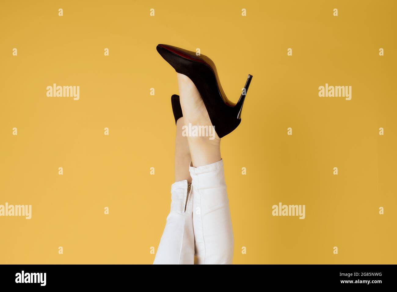 female inverted legs in black shoes cropped view yellow background ...