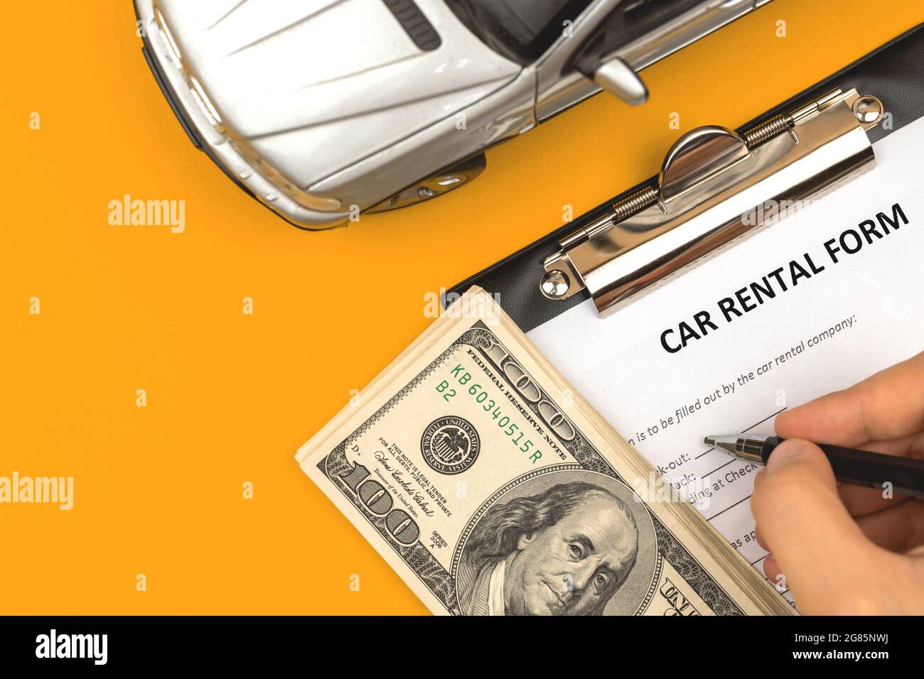 Man filling car rental form. Clipboard on office table with dollars and ...