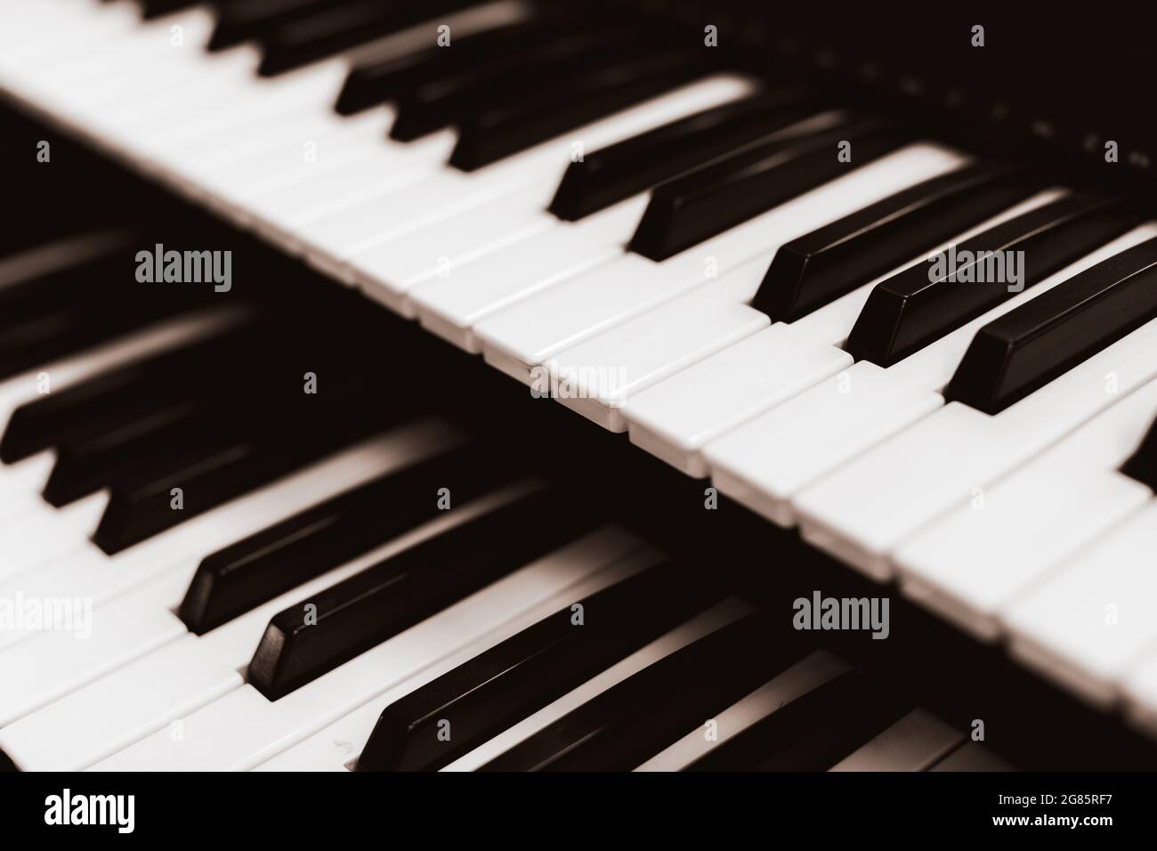 Close focus on upper row of piano keyboard with warm tone of black and ...
