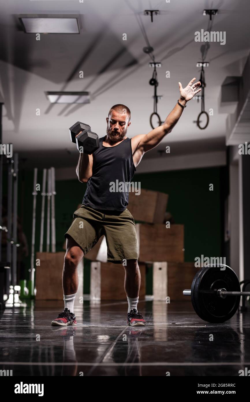 Muscular athlete lifting very heavy weights. Man working out indoors ...