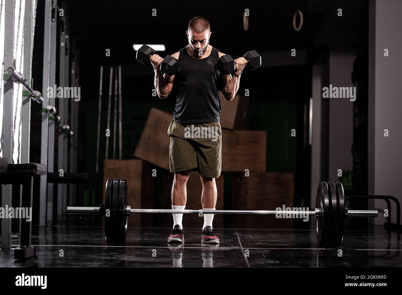 Muscular athlete lifting weights. Standing in front of heavy barbell ...