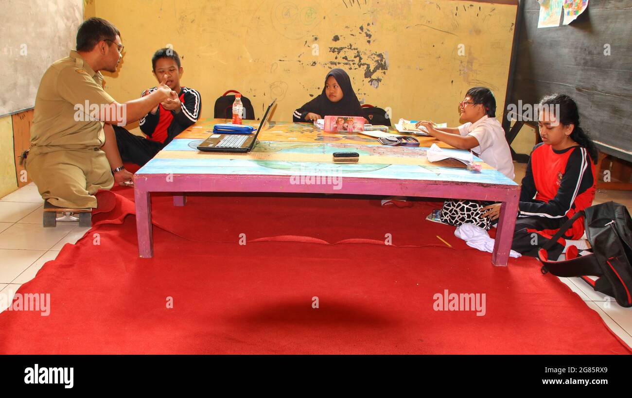 teacher with disabilities (without legs), eagerly teaches his students ...