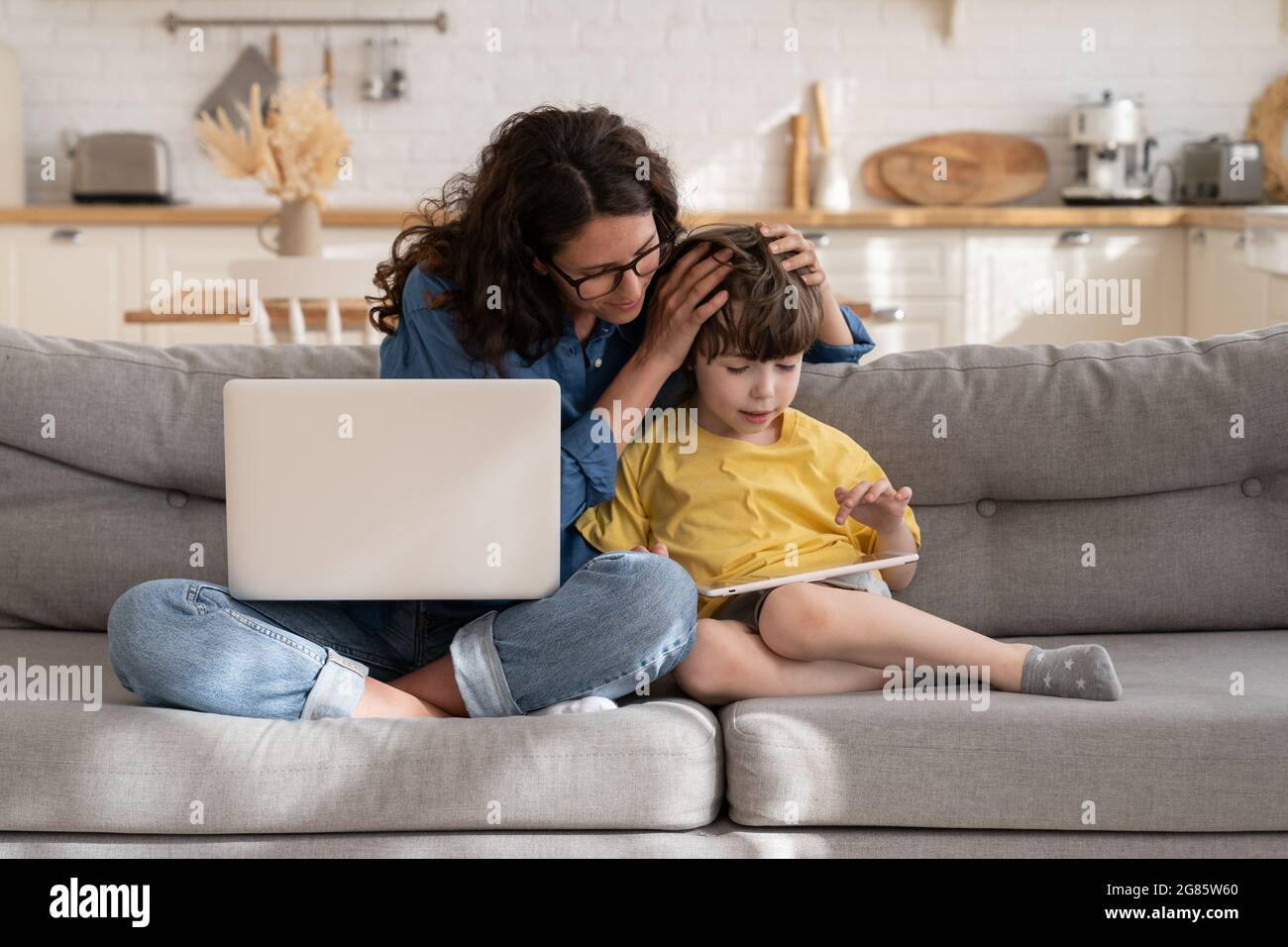 Caring mom help preschool kid with e-learning on digital tablet as work ...